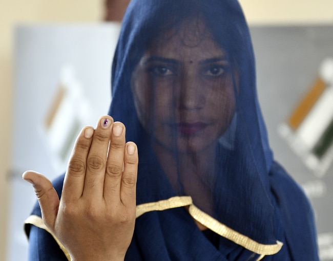 A woman voter shows her ink marked finger after casting her vote for ...