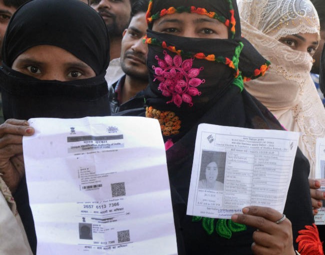 Muslim women showing their Aadhaar Card while standing in queue